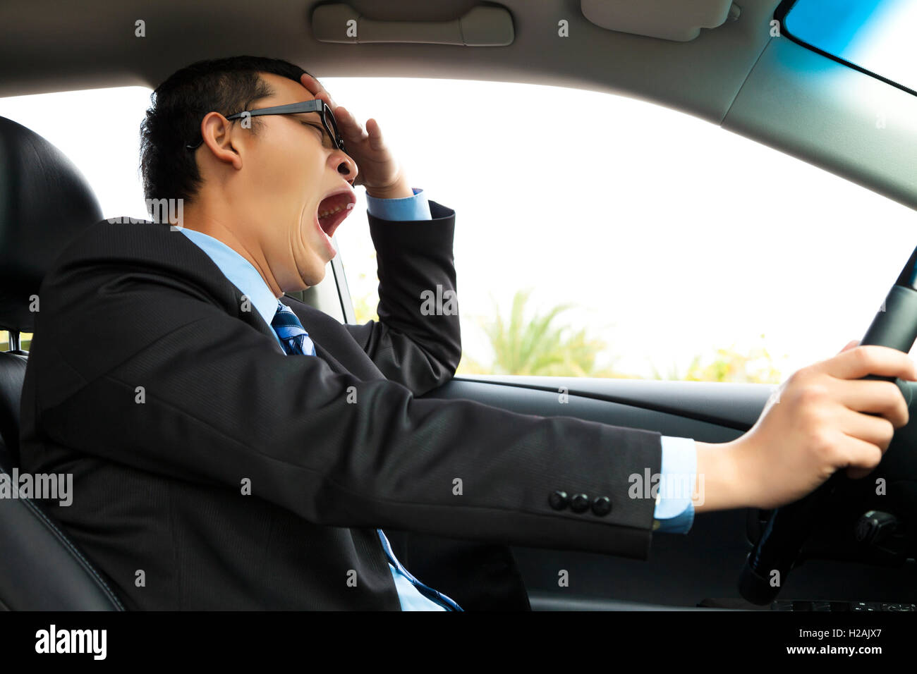 Exhausted driver yawning and driving car Stock Photo - Alamy