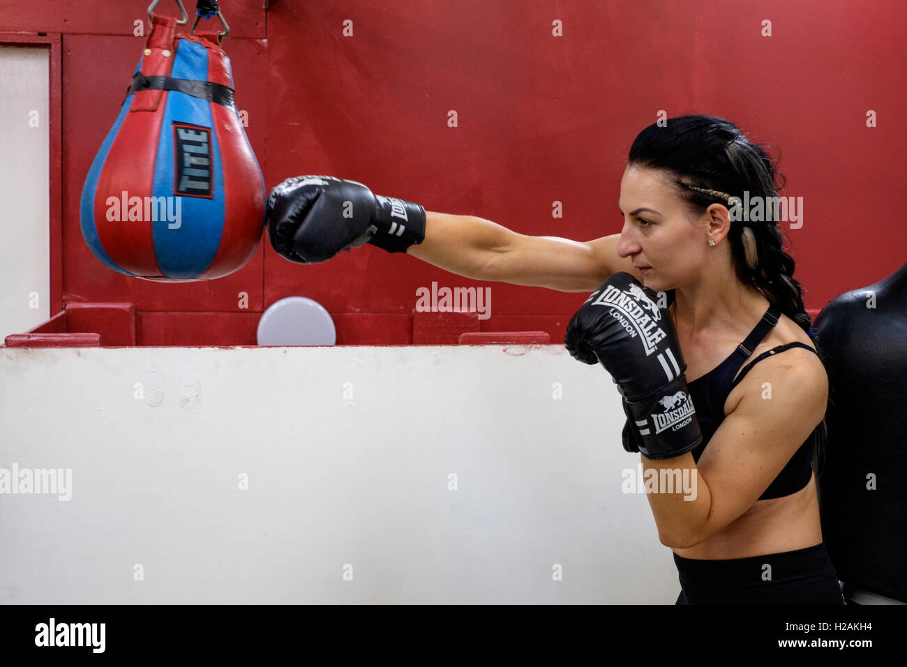young female working out in a gym boxing with a punch bag england uk ...