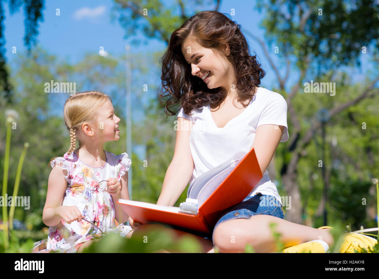 girl and a young woman reading a book together Stock Photo - Alamy