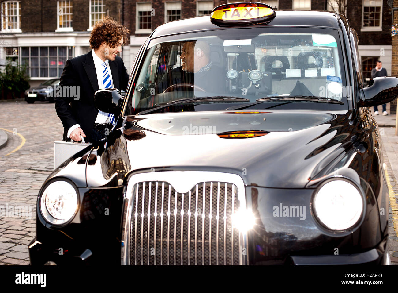 Corporate guy interacting with taxi driver Stock Photo - Alamy