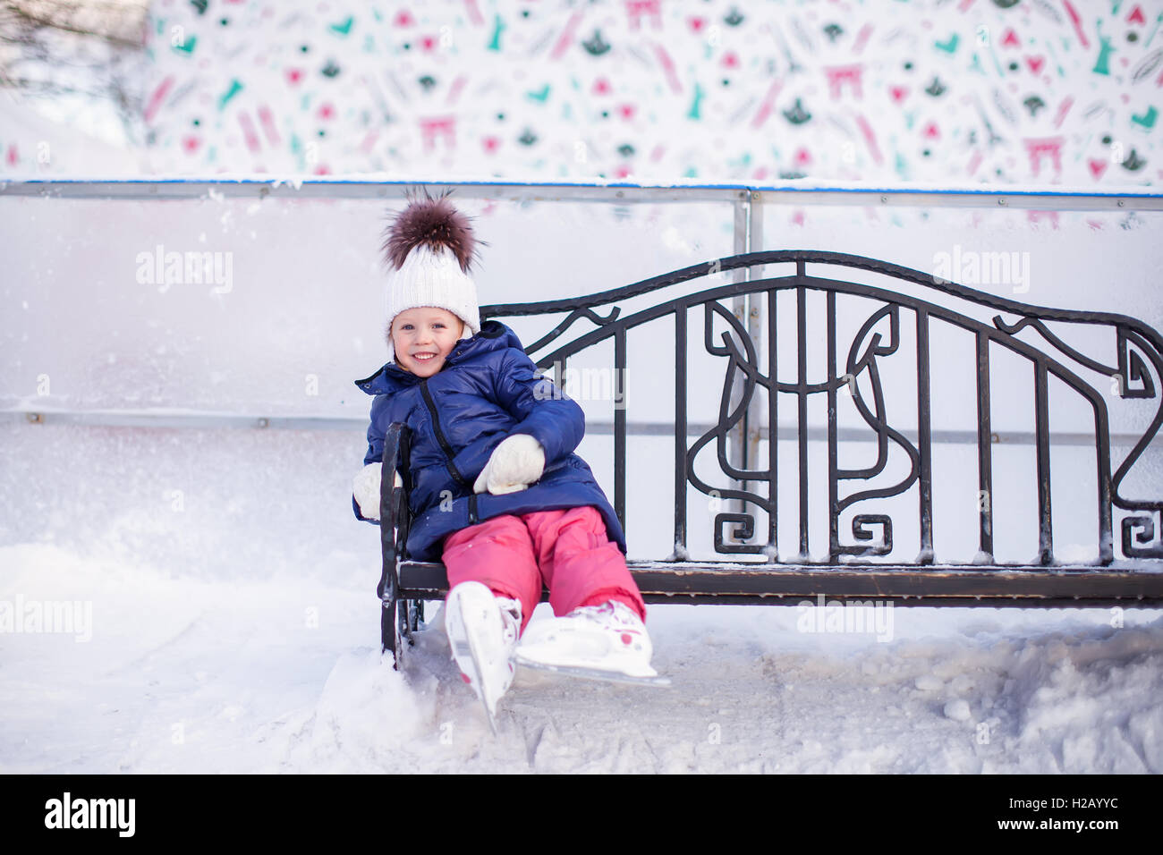 Little girl sitting on a bench in the skating rink Stock Photo - Alamy