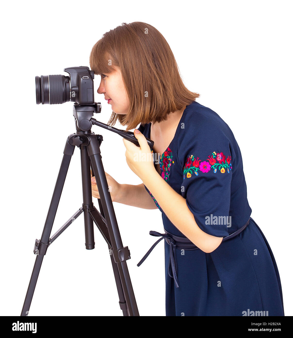 Woman photographer looking into the camera lens on a tripod isolated on ...