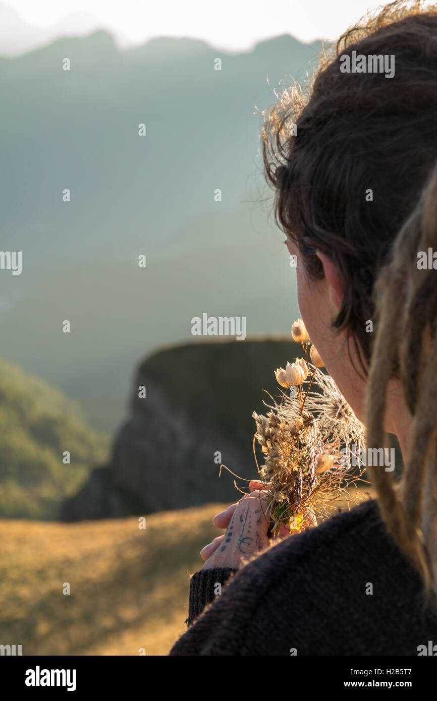Woman sitting in the Italian mountains with flowers in the hand ...