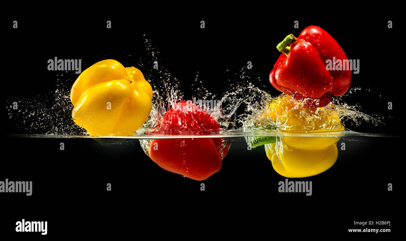 Group of bell pepper falling in water with splash on black background ...
