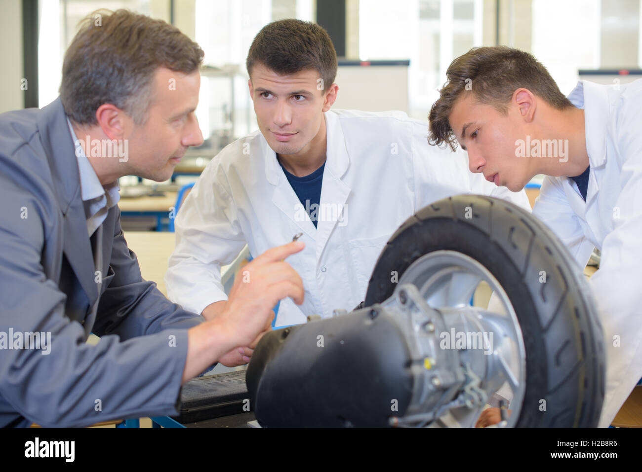 Engineer and students looking at wheel Stock Photo - Alamy
