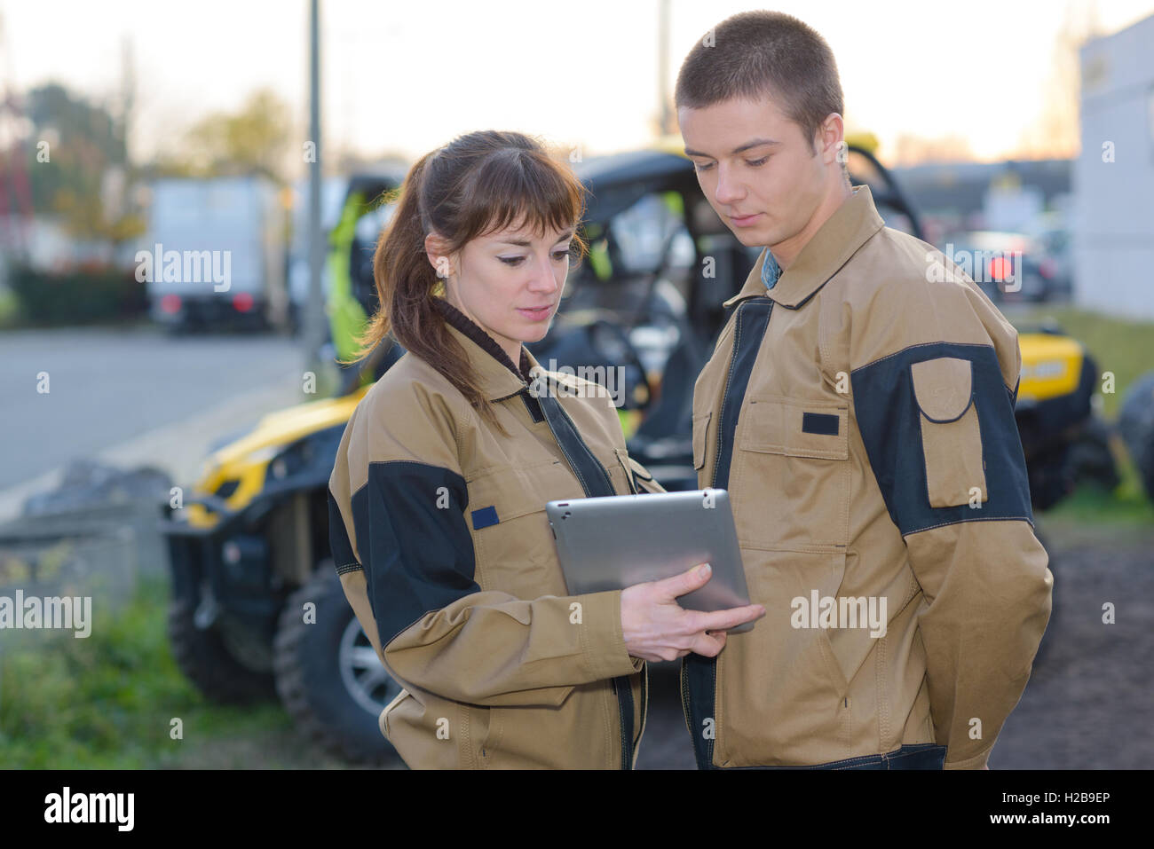 mechanics looking at computer tablet in front of parked quads Stock ...