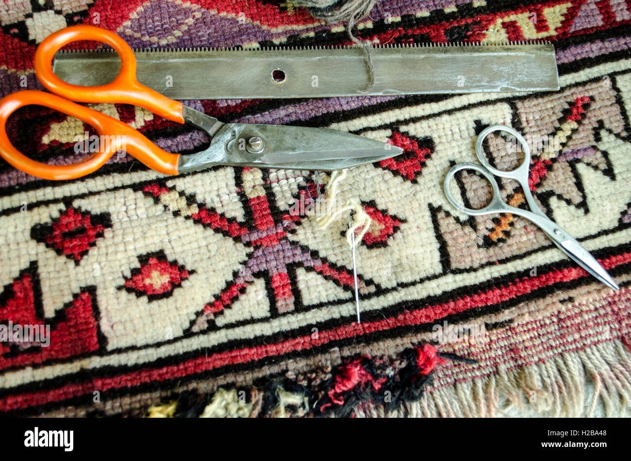 Worn old woolen carpet with tools Stock Photo - Alamy