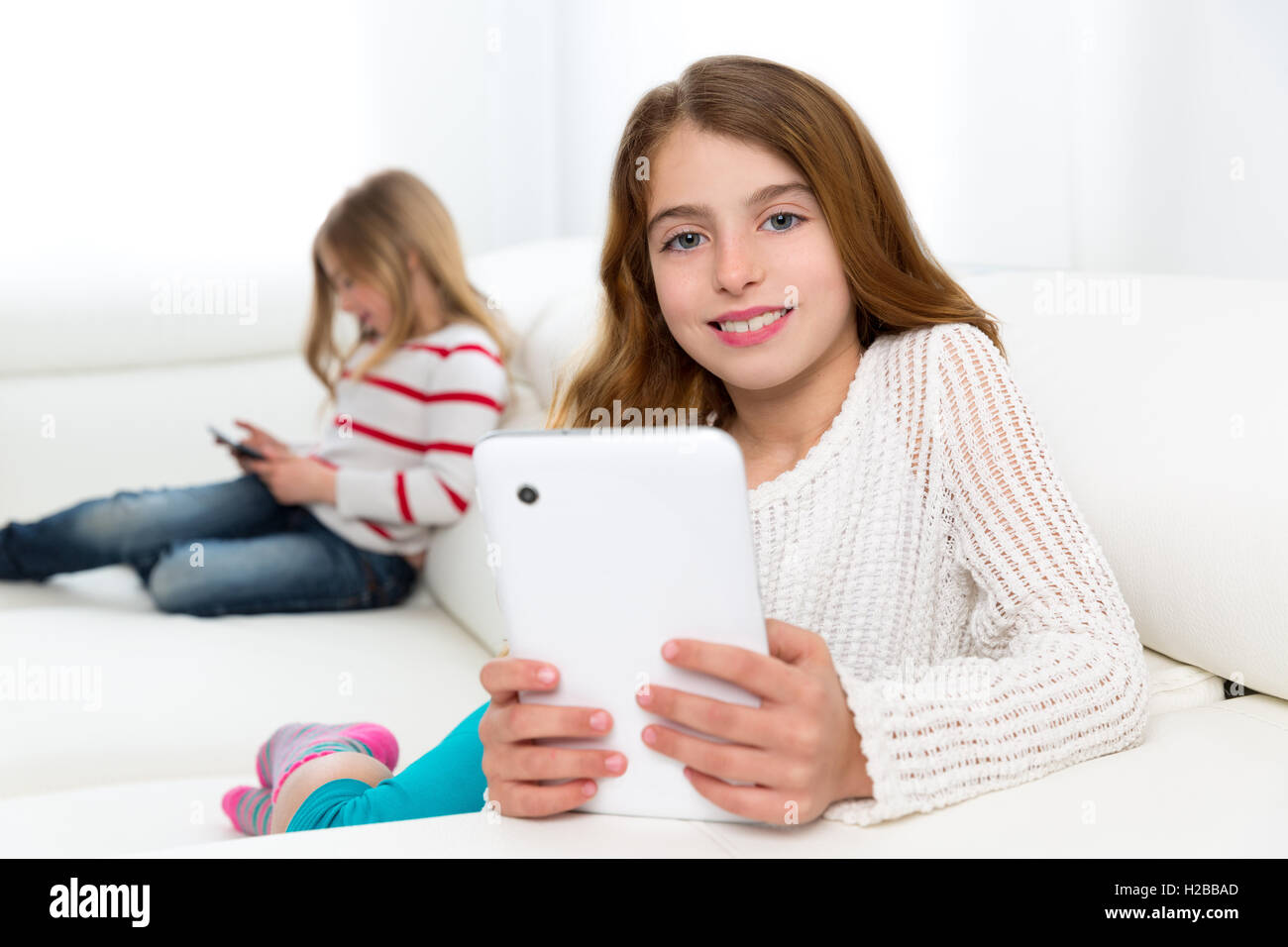 sister friends kid girls playing with tablet pc in sofa Stock Photo - Alamy