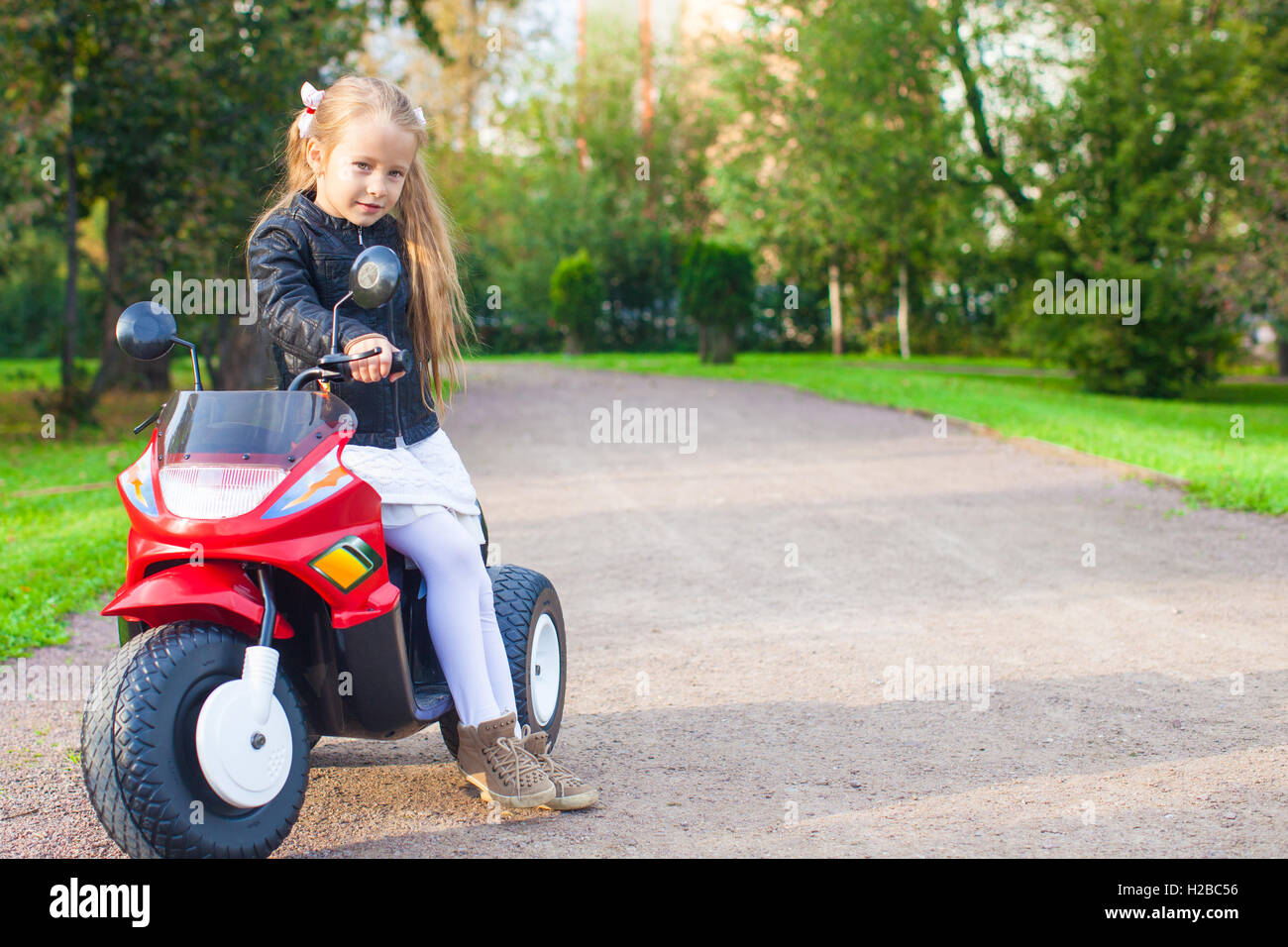 Adorable little girl having fun on her toy motorcycle Stock Photo - Alamy