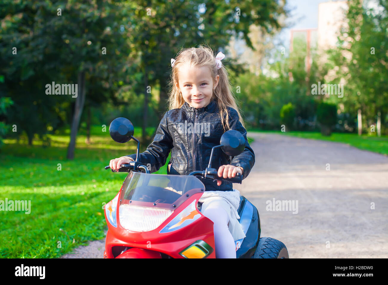 Little adorable girl on her toy motorcycle Stock Photo - Alamy