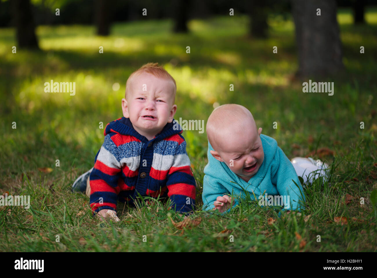 two crying children lying in grass Stock Photo - Alamy