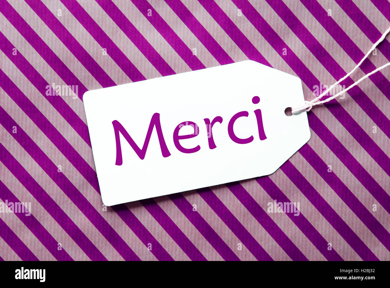 Label On Purple Wrapping Paper, Merci Means Thank You Stock Photo - Alamy
