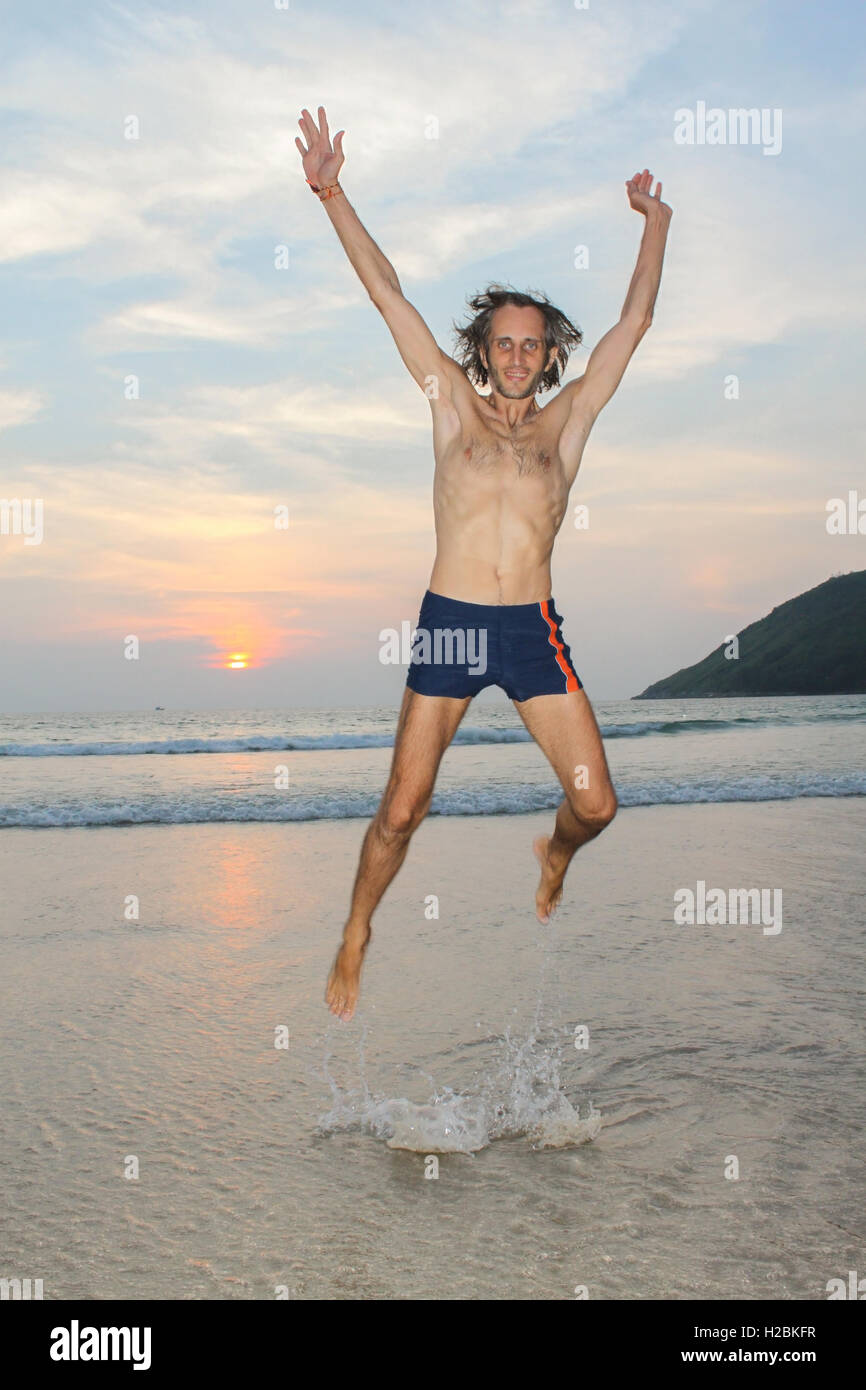 a jumping happy in the beach with a sunset in the background Stock ...
