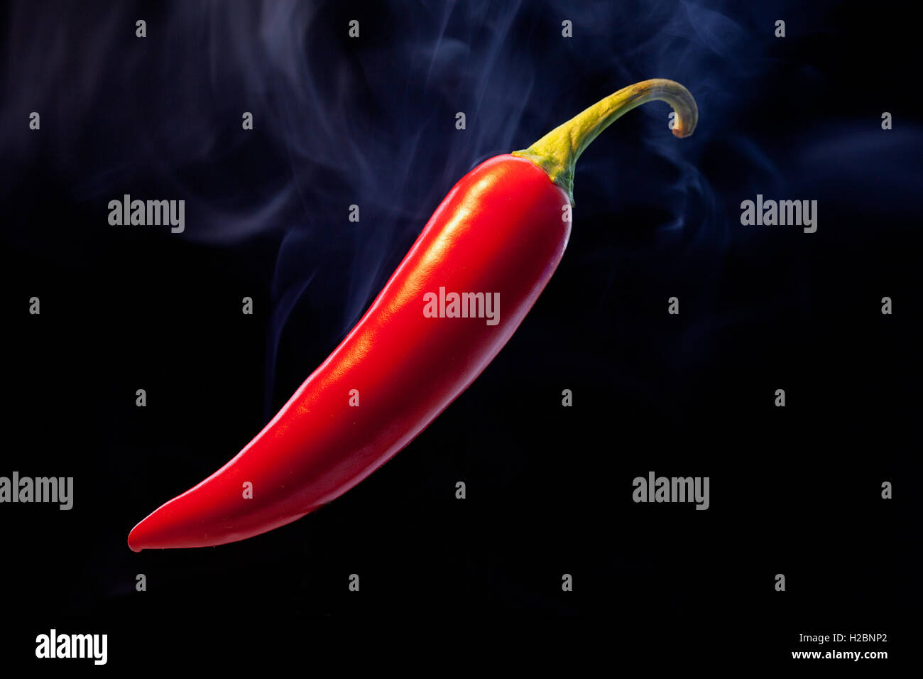 Smoking red chilli pepper on black background Stock Photo - Alamy