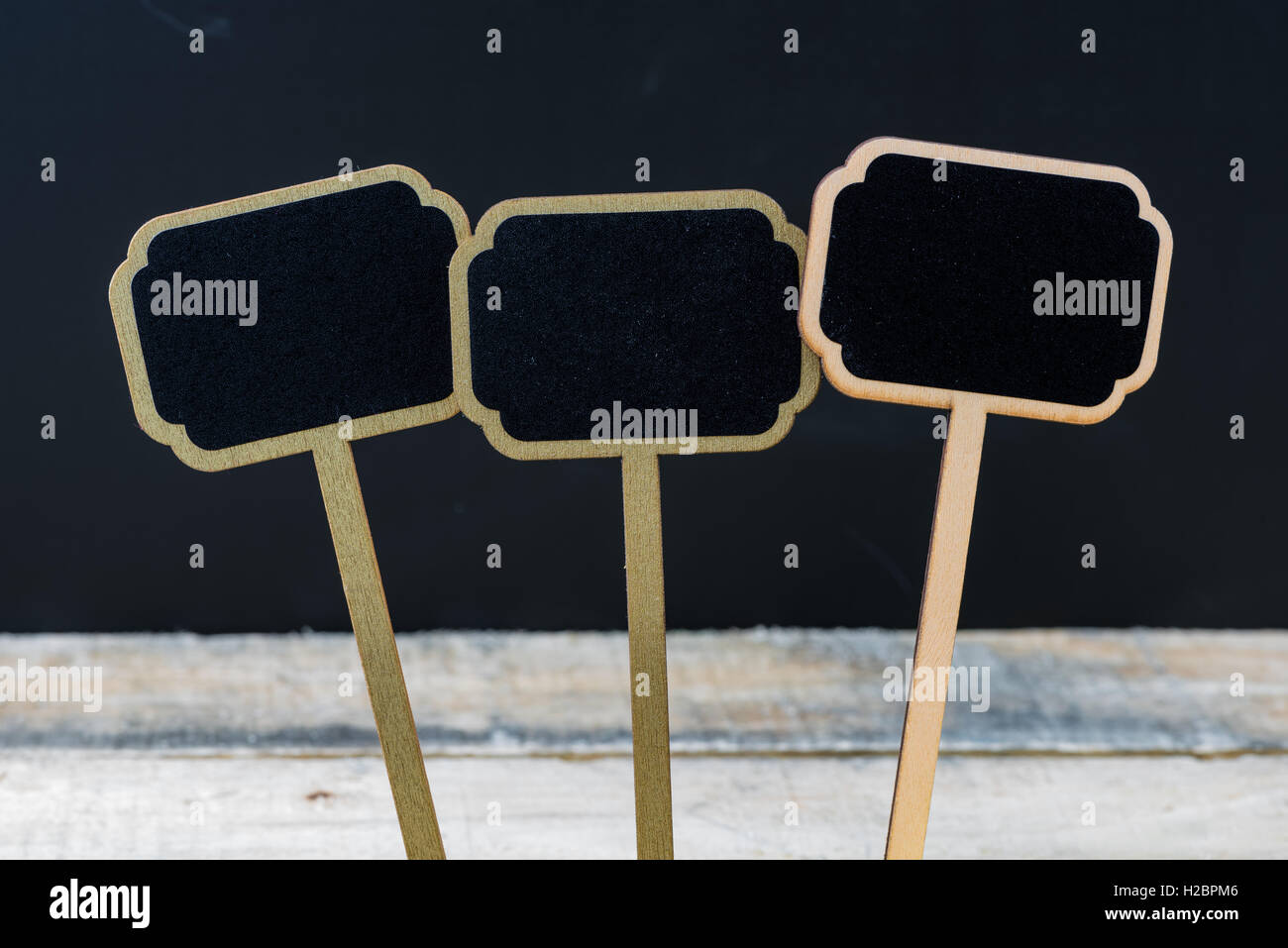 Wooden mini blackboard labels over chalkboard background and table ...