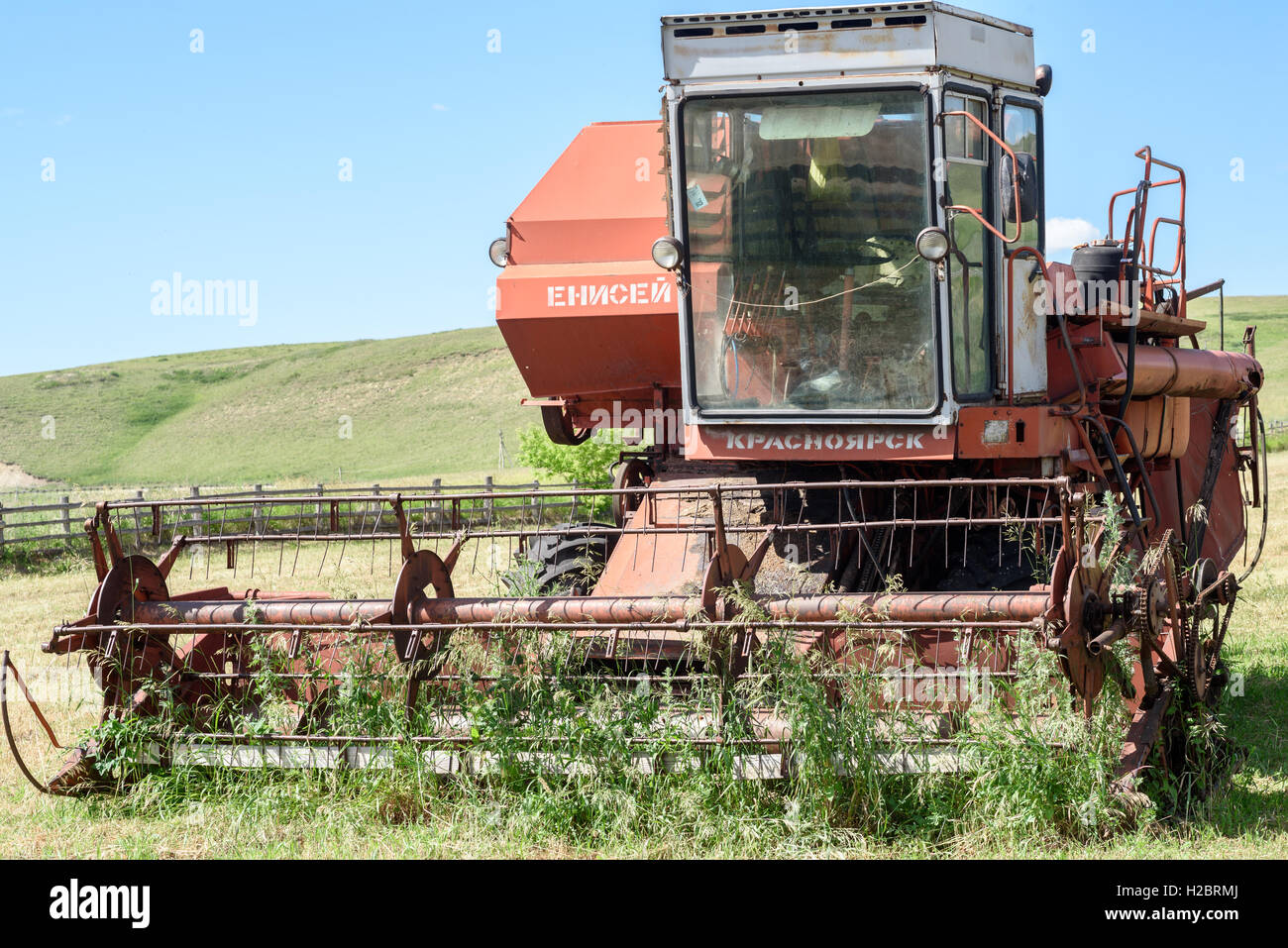 Single deserted red combine harvester in the summer sun in a field in ...