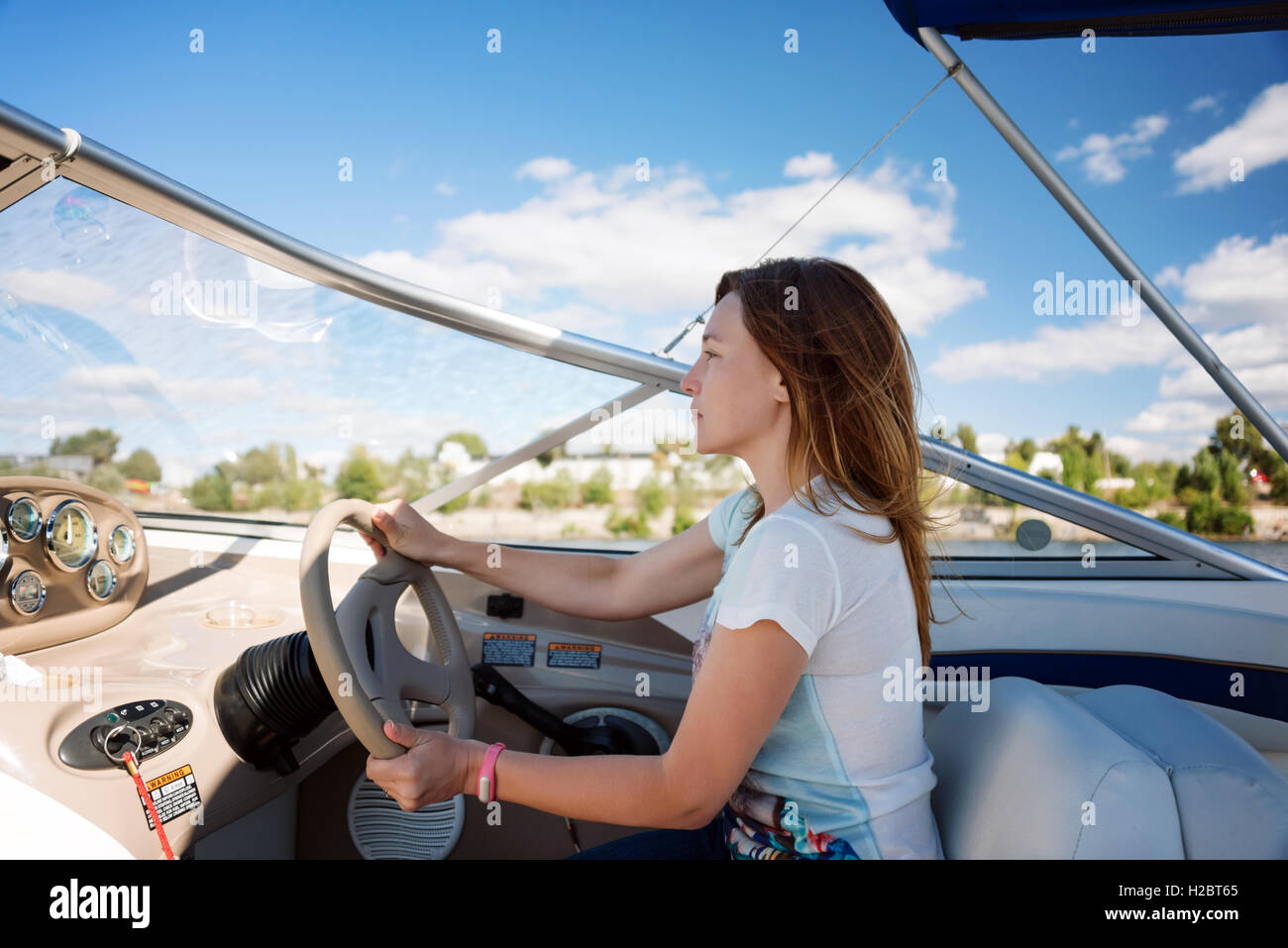 Woman behind the wheel yacht, enjoying nature and river landscape ...