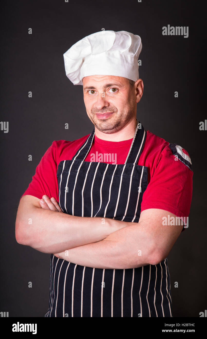 Handsome chef with crossed arms posing against black background Stock ...