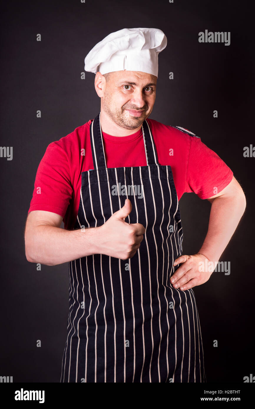 Portrait of a cook man doing a success symbol against a black ...