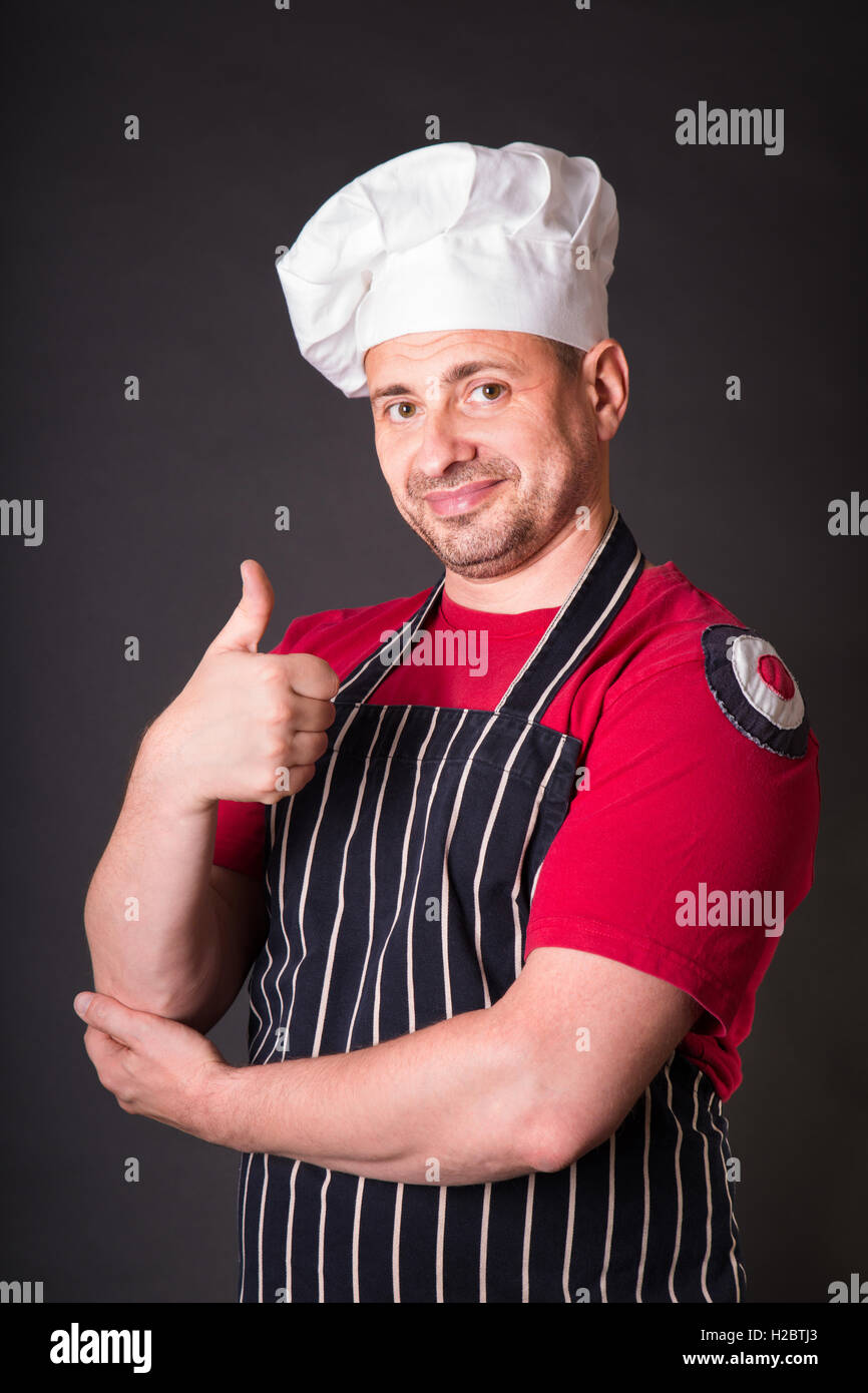 Portrait of a cook man doing a success symbol against a black ...