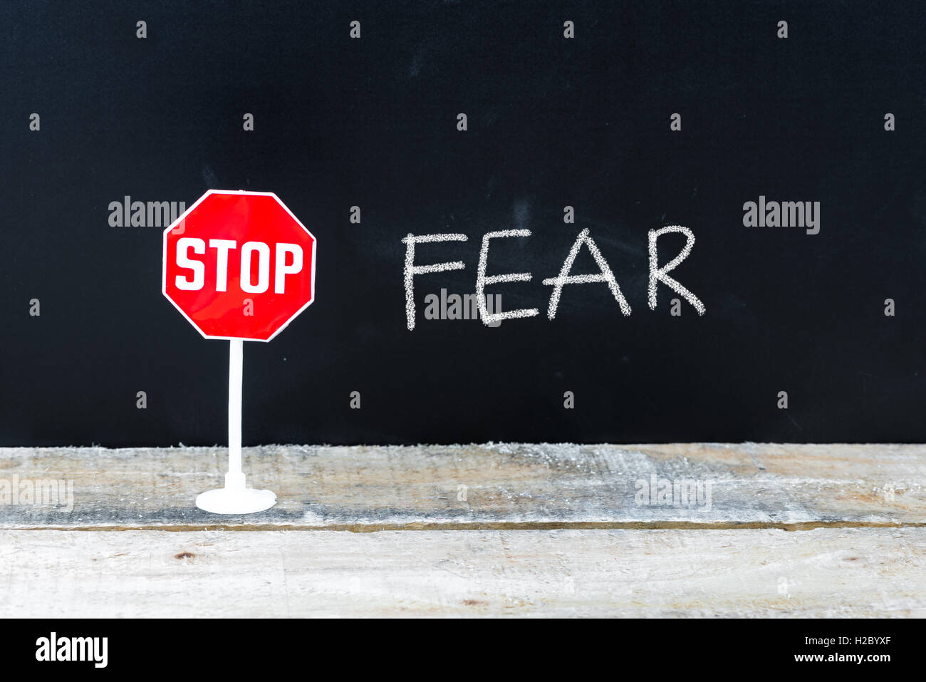 Mini STOP sign over chalkboard background and table, STOP FEAR concept ...