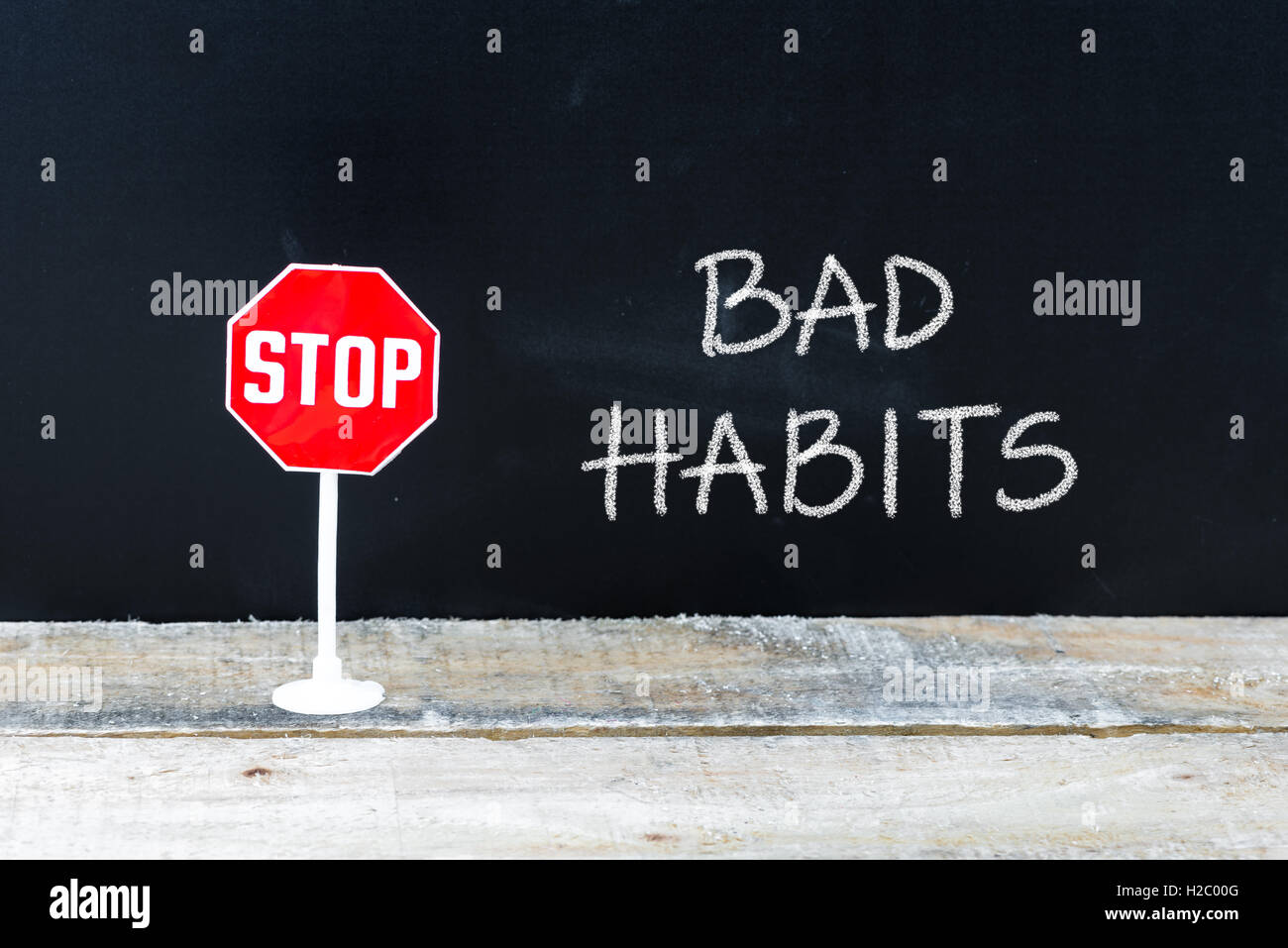 Mini STOP sign over chalkboard background and table, STOP BAD HABITS ...
