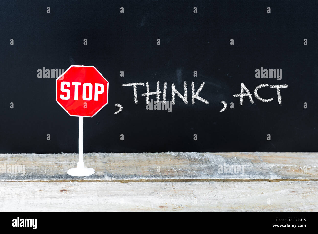 Mini STOP sign over chalkboard background and table, STOP, THINK, ACT ...