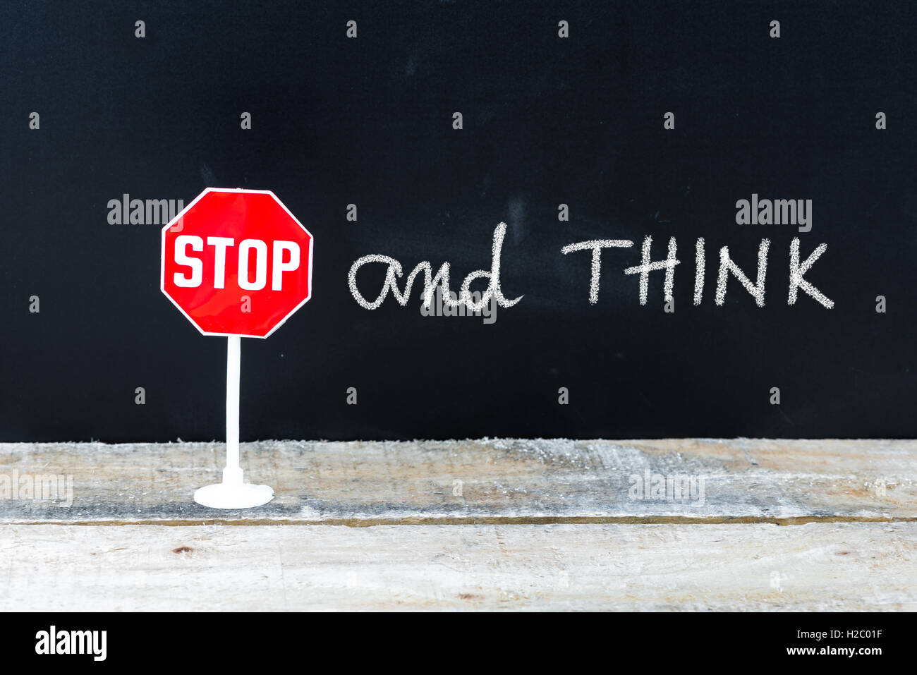 Mini STOP sign over chalkboard background and table, STOP and THINK ...