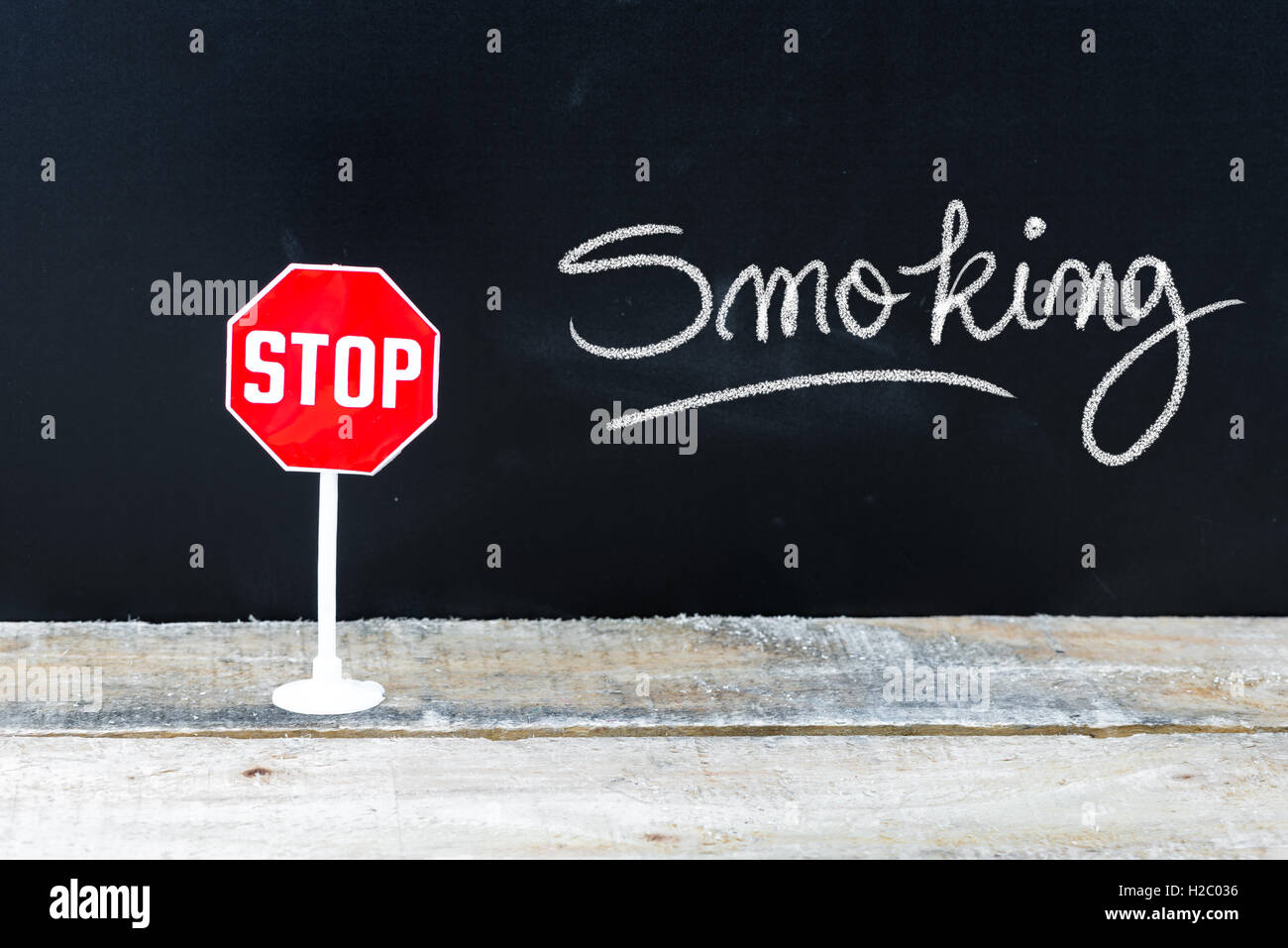 Mini STOP sign over chalkboard background and table, STOP SMOKING ...