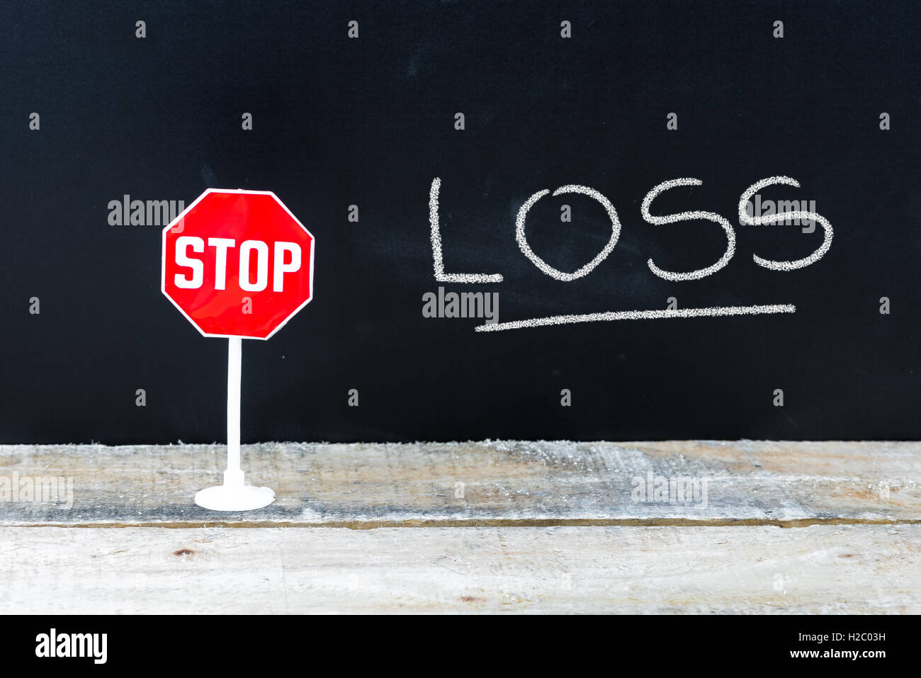 Mini STOP sign over chalkboard background and table, STOP LOSS concept ...