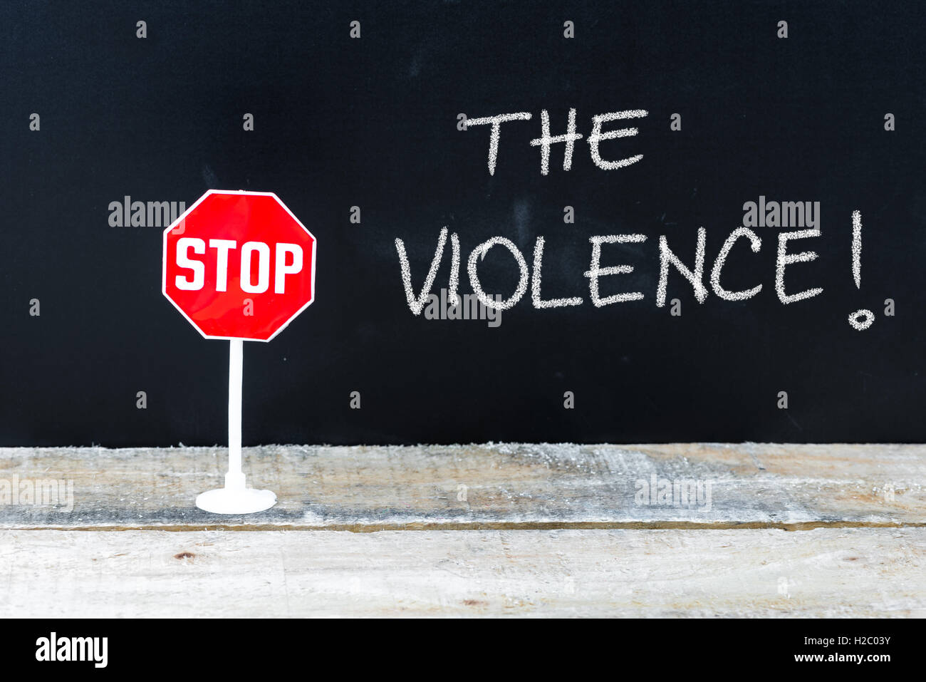 Mini STOP sign over chalkboard background and table, STOP THE VIOLENCE ...
