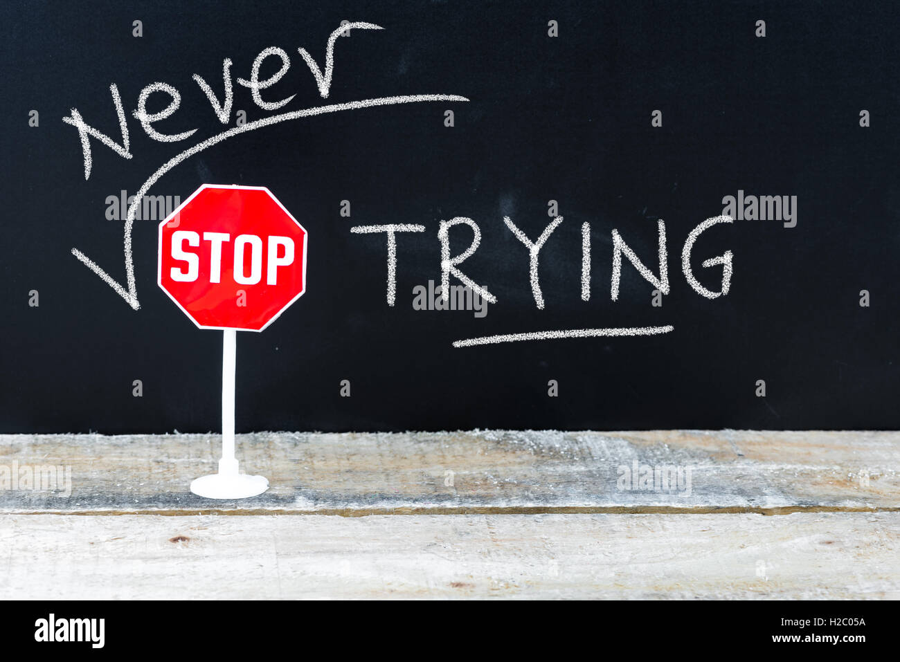 Mini STOP sign over chalkboard background and table, NEVER STOP TRYING ...