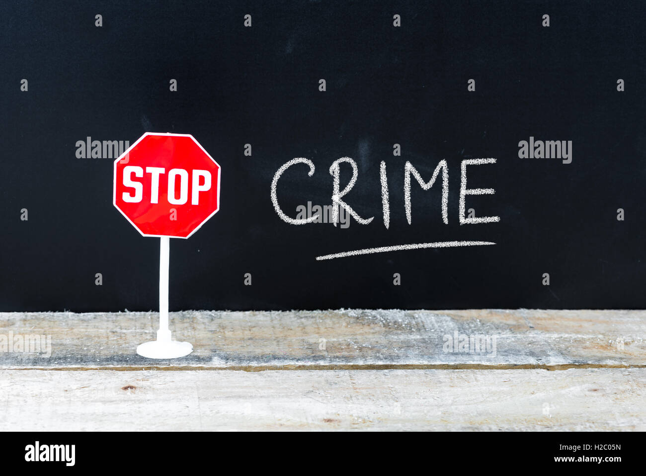 Mini STOP sign over chalkboard background and table, STOP CRIME concept ...