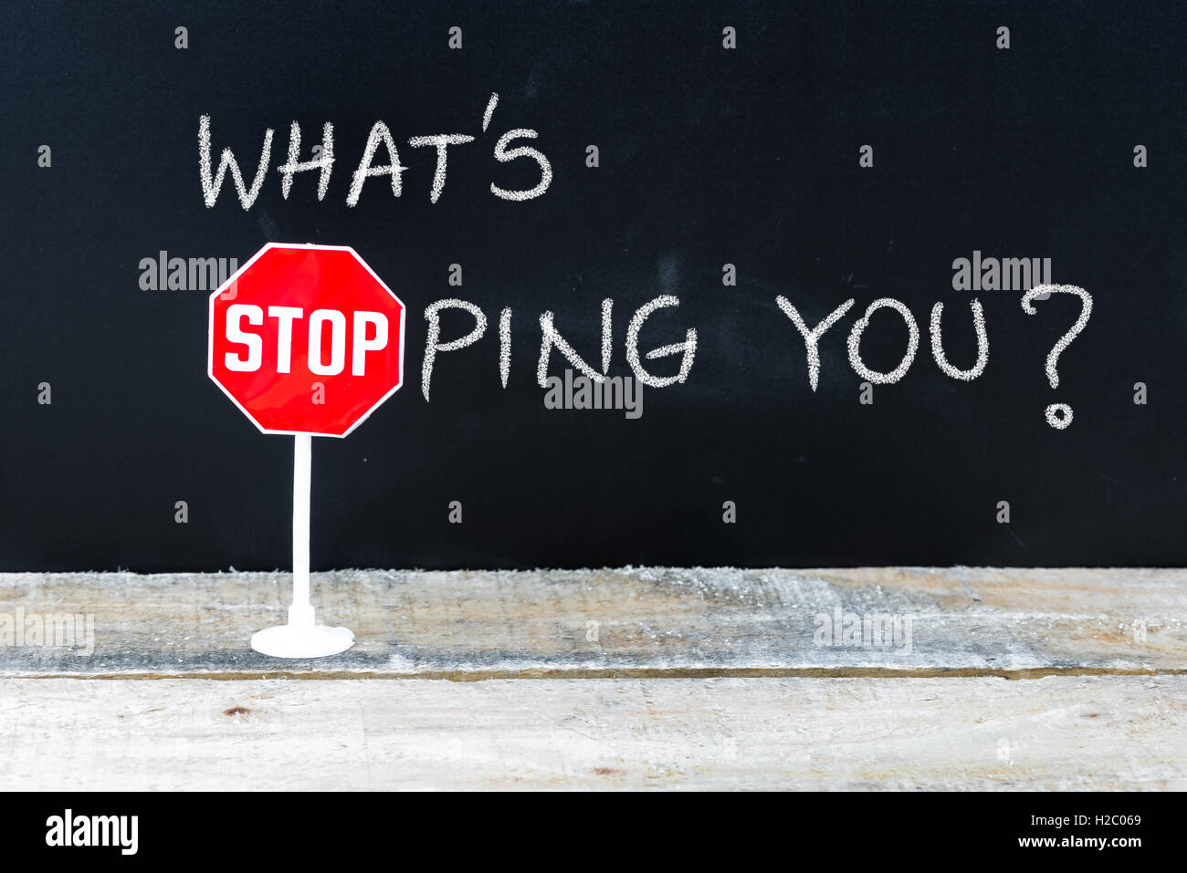 Mini STOP sign over chalkboard background and table, WHAT IS STOPPING ...