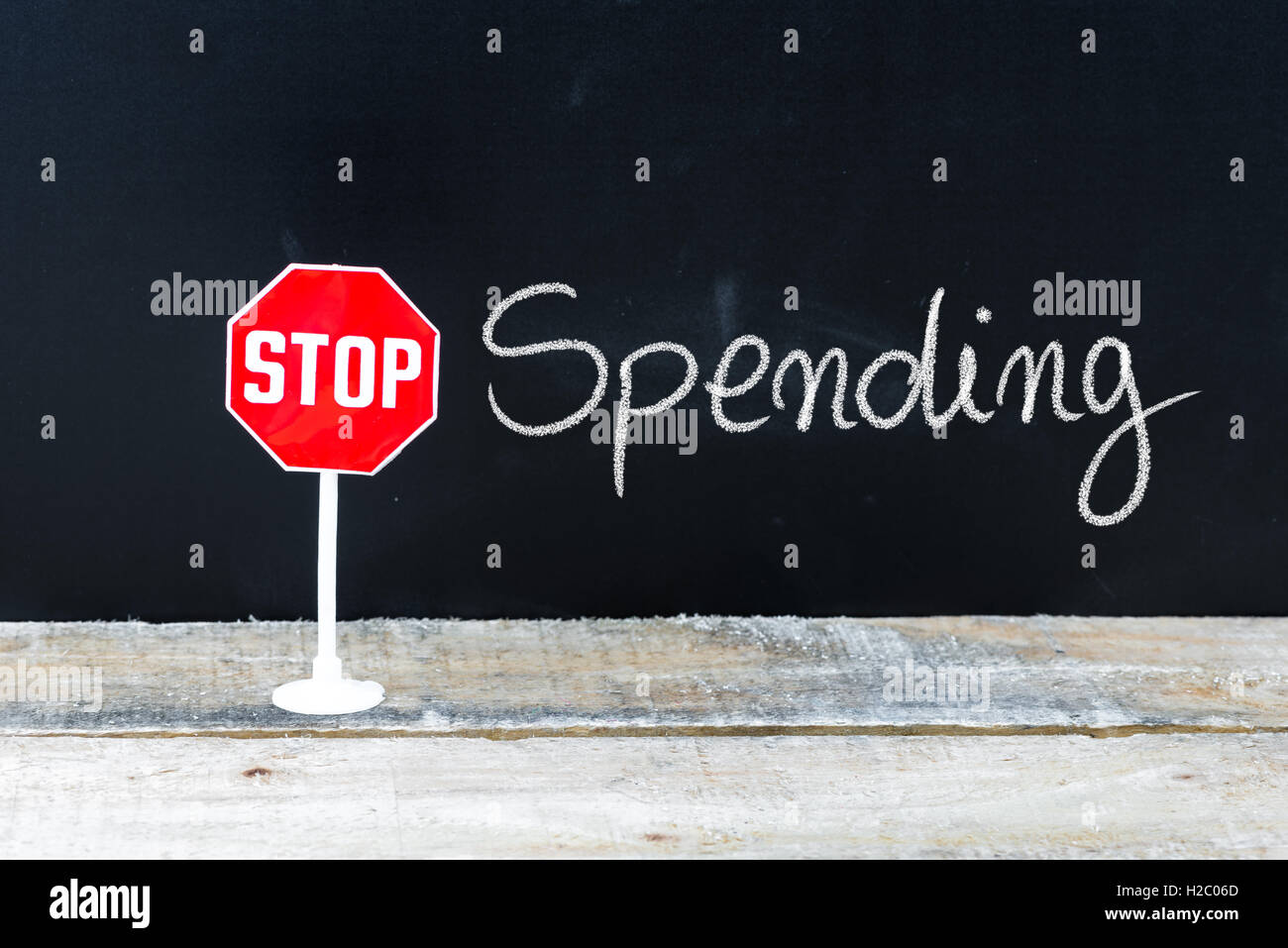 Mini STOP sign over chalkboard background and table, STOP SPENDING ...