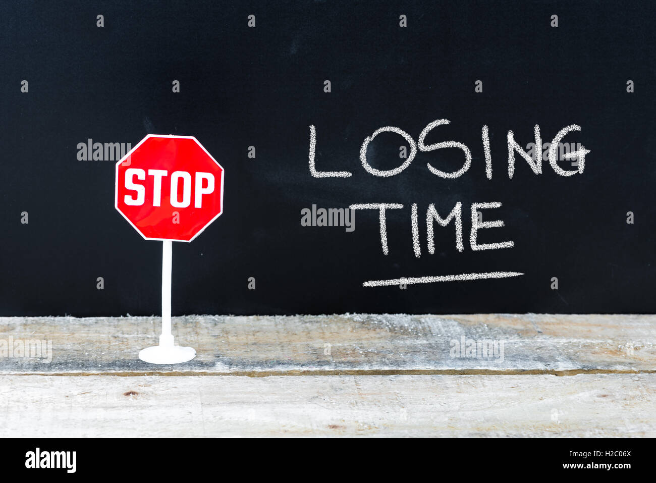Mini STOP sign over chalkboard background and table, STOP LOSING TIME ...