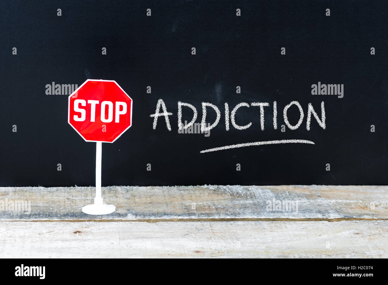 Mini STOP sign over chalkboard background and table, STOP ADDICTION ...