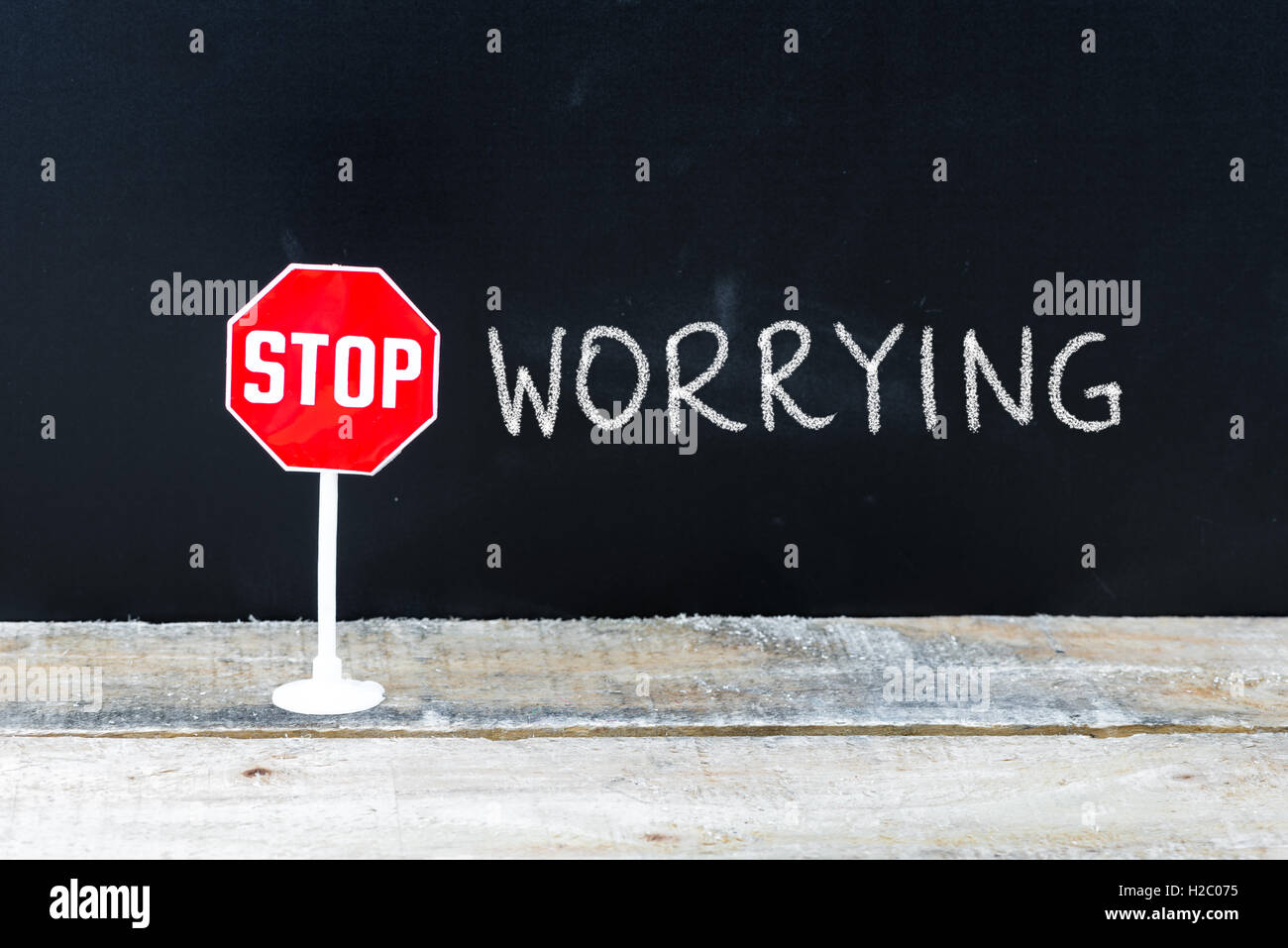 Mini STOP sign over chalkboard background and table, STOP WORRYING ...