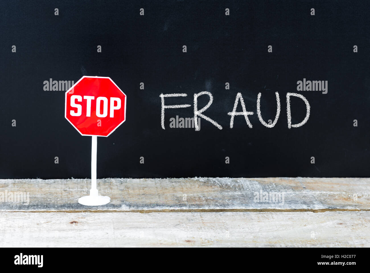 Mini STOP sign over chalkboard background and table, STOP FRAUD concept ...