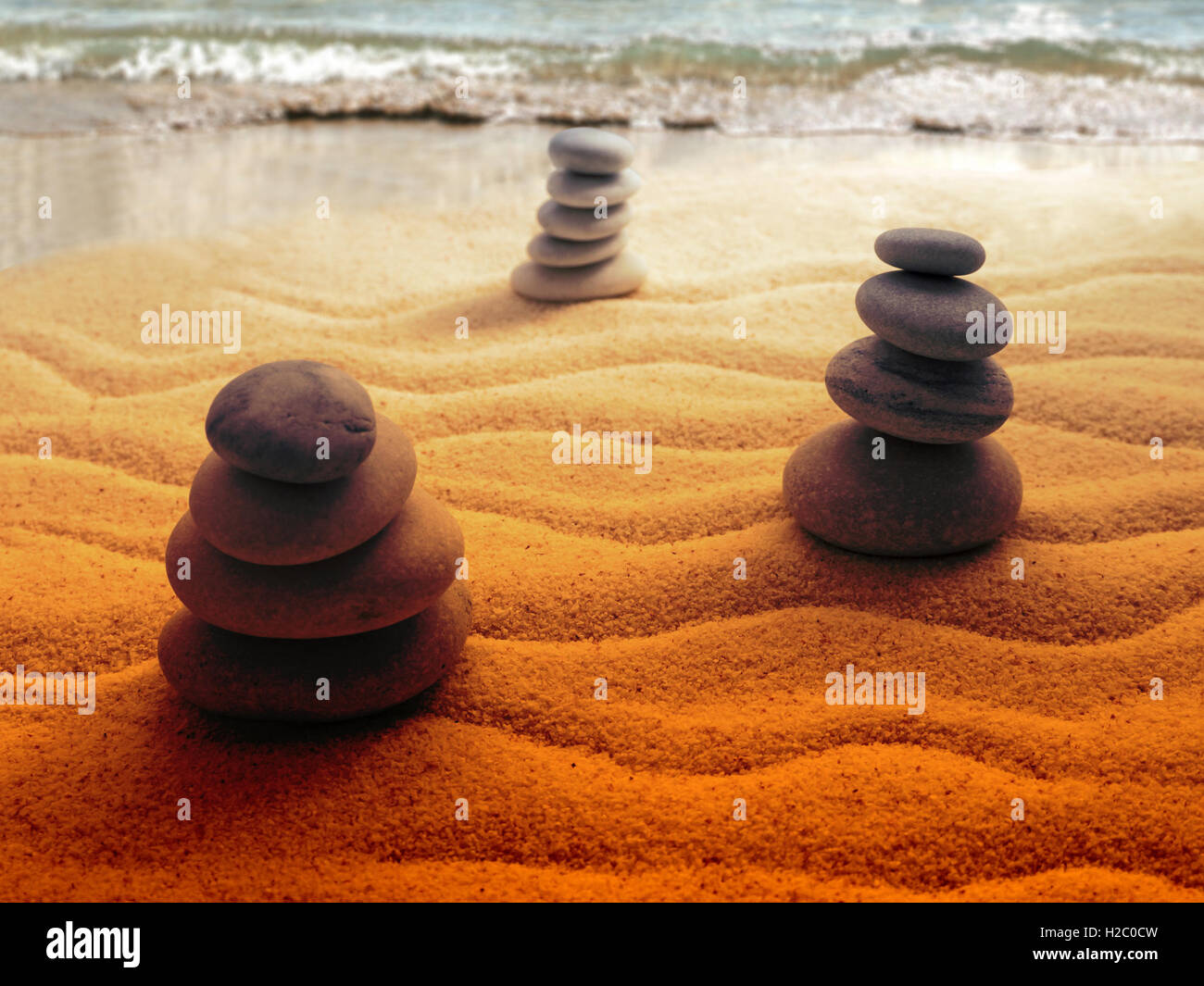 Three pyramides of stones on the beach at sunset Stock Photo - Alamy
