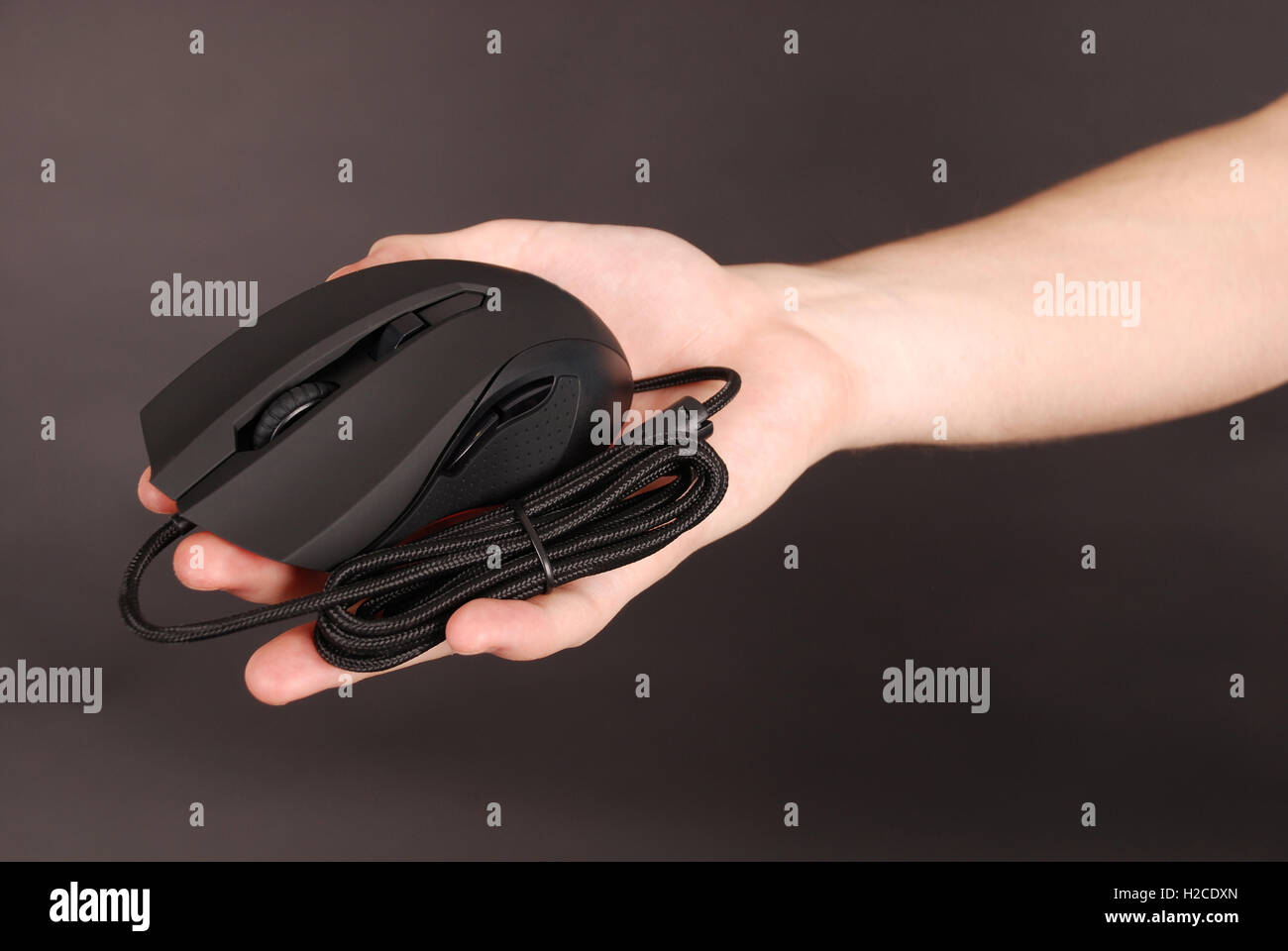 Man holds in his hand black computer optical mouse isolated on black ...