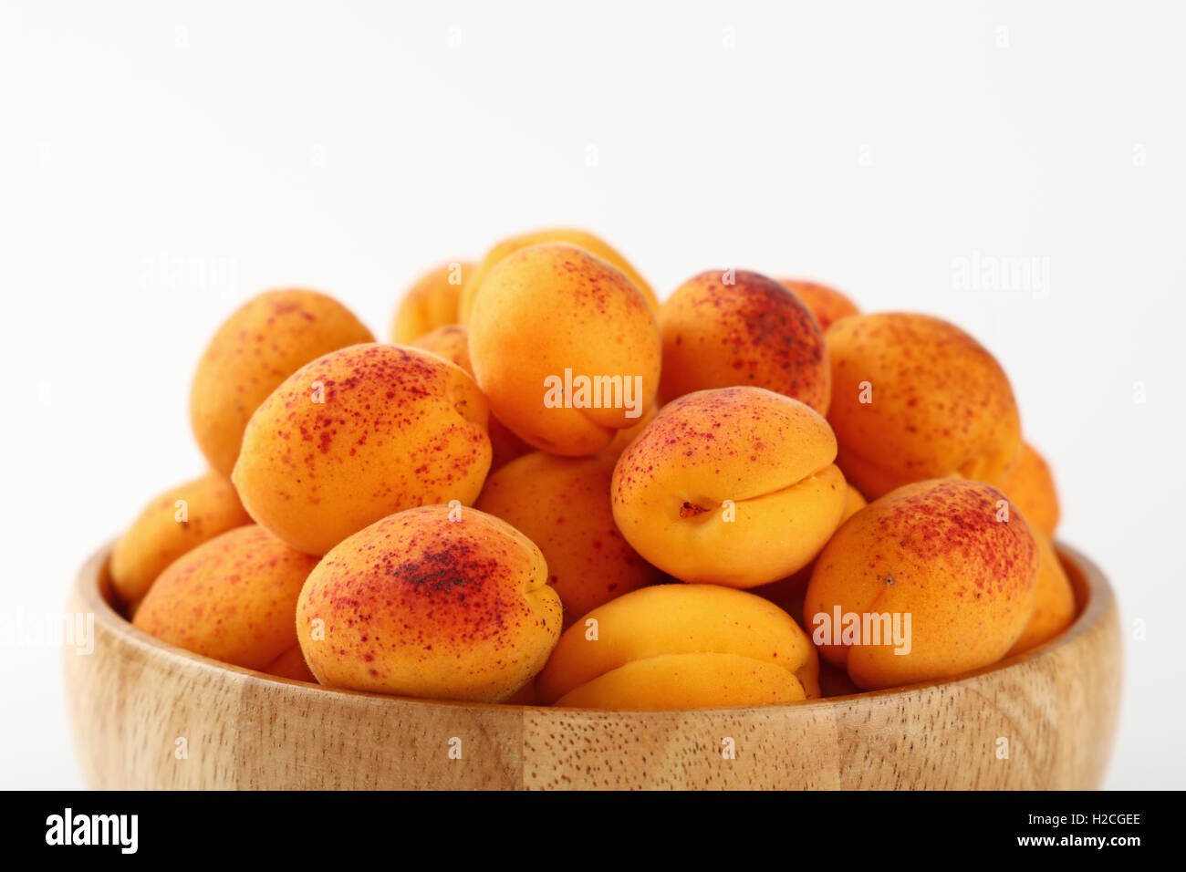 Mellow ripe fresh apricots with in big wooden bowl isolated on white ...