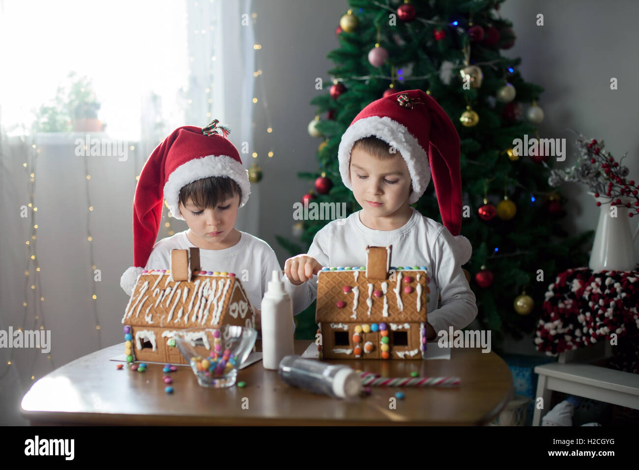 Two sweet boys, brothers, making gingerbread cookies house, decorating ...