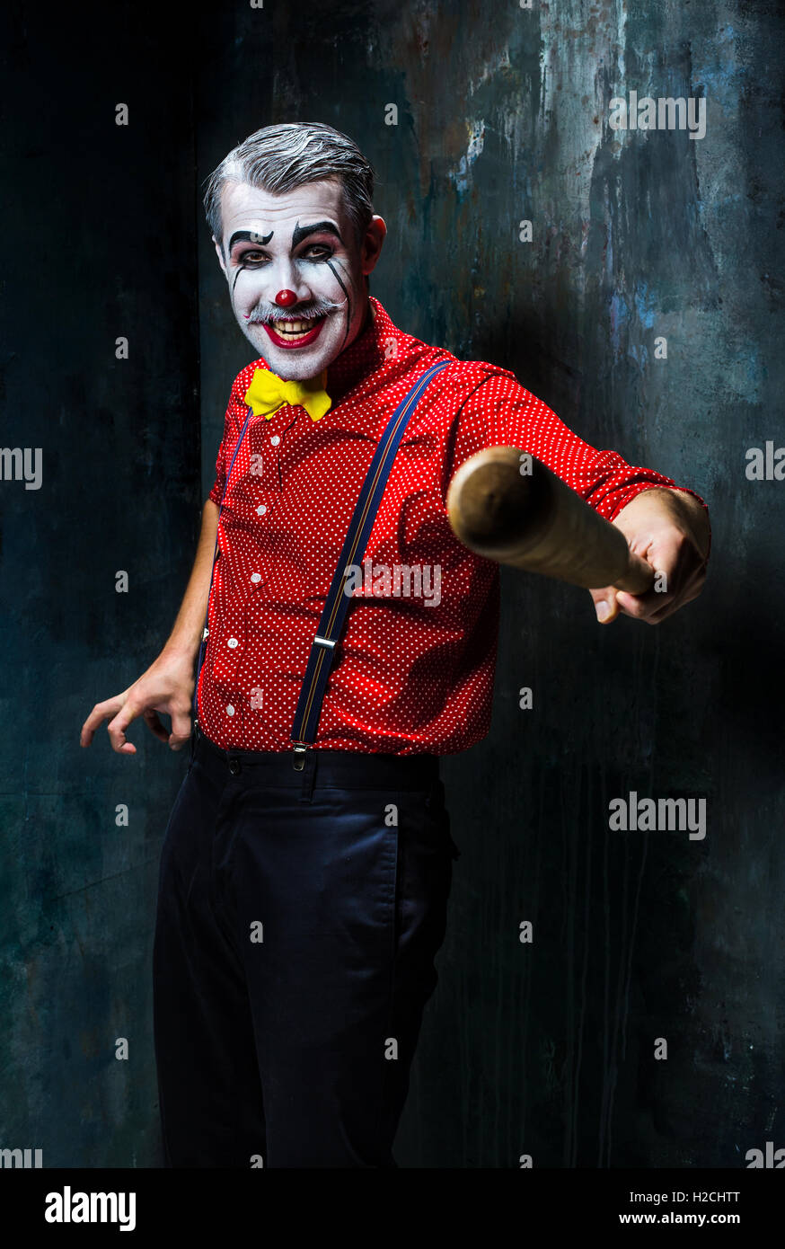 The scary clown and baseball-bat on dack background. Halloween concept ...