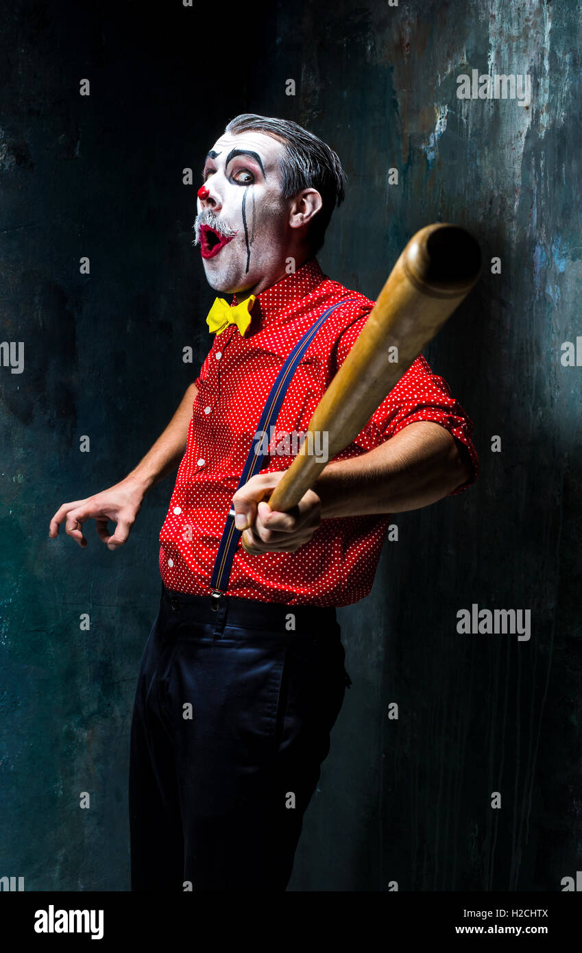 The scary clown and baseball-bat on dack background. Halloween concept ...