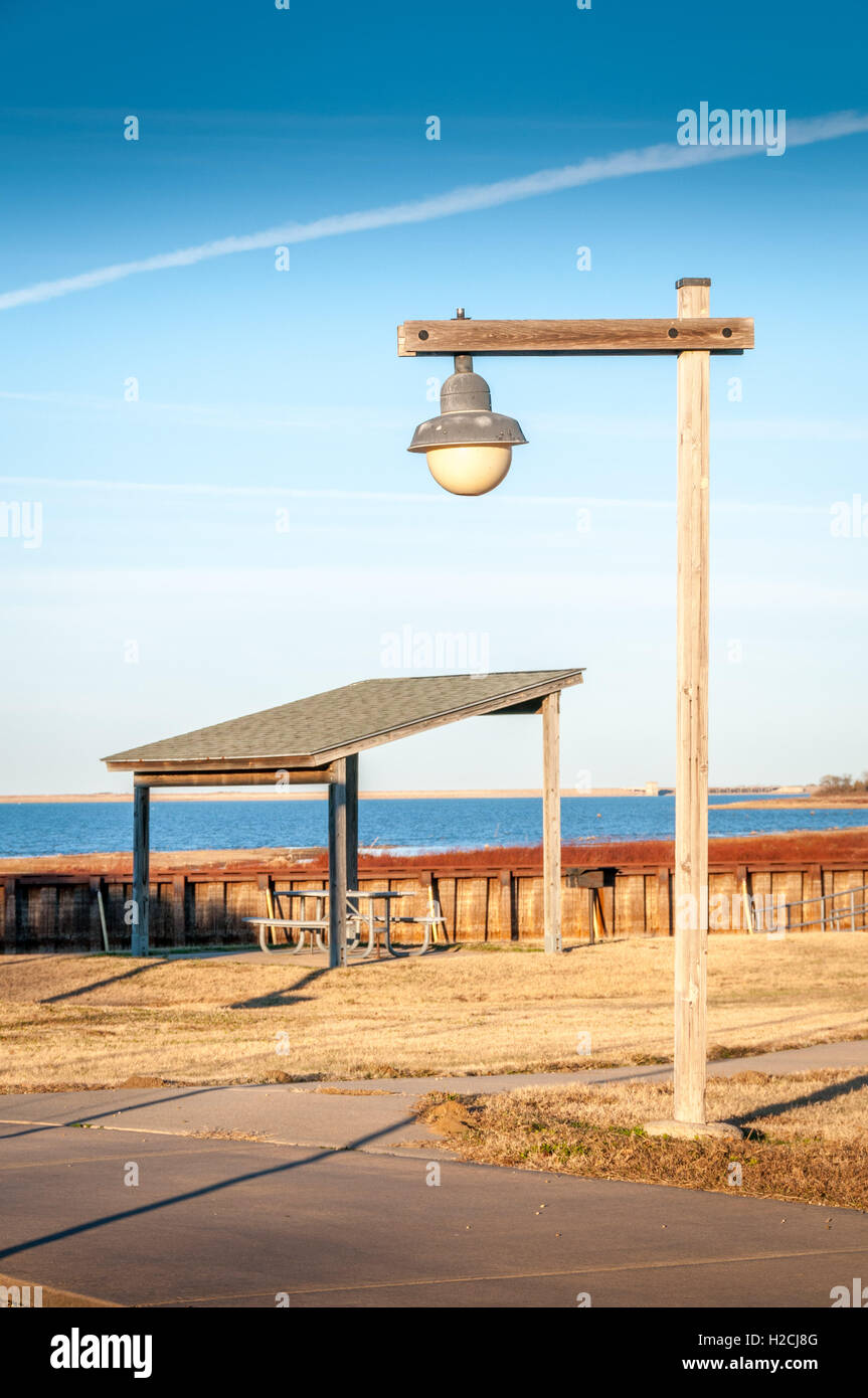 street lamp, picnic table, and its pavilion by a clear blue fresh water ...