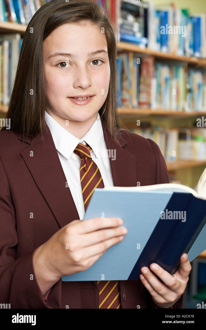 Girl Wearing School Uniform Reading Book In Library Stock Photo - Alamy