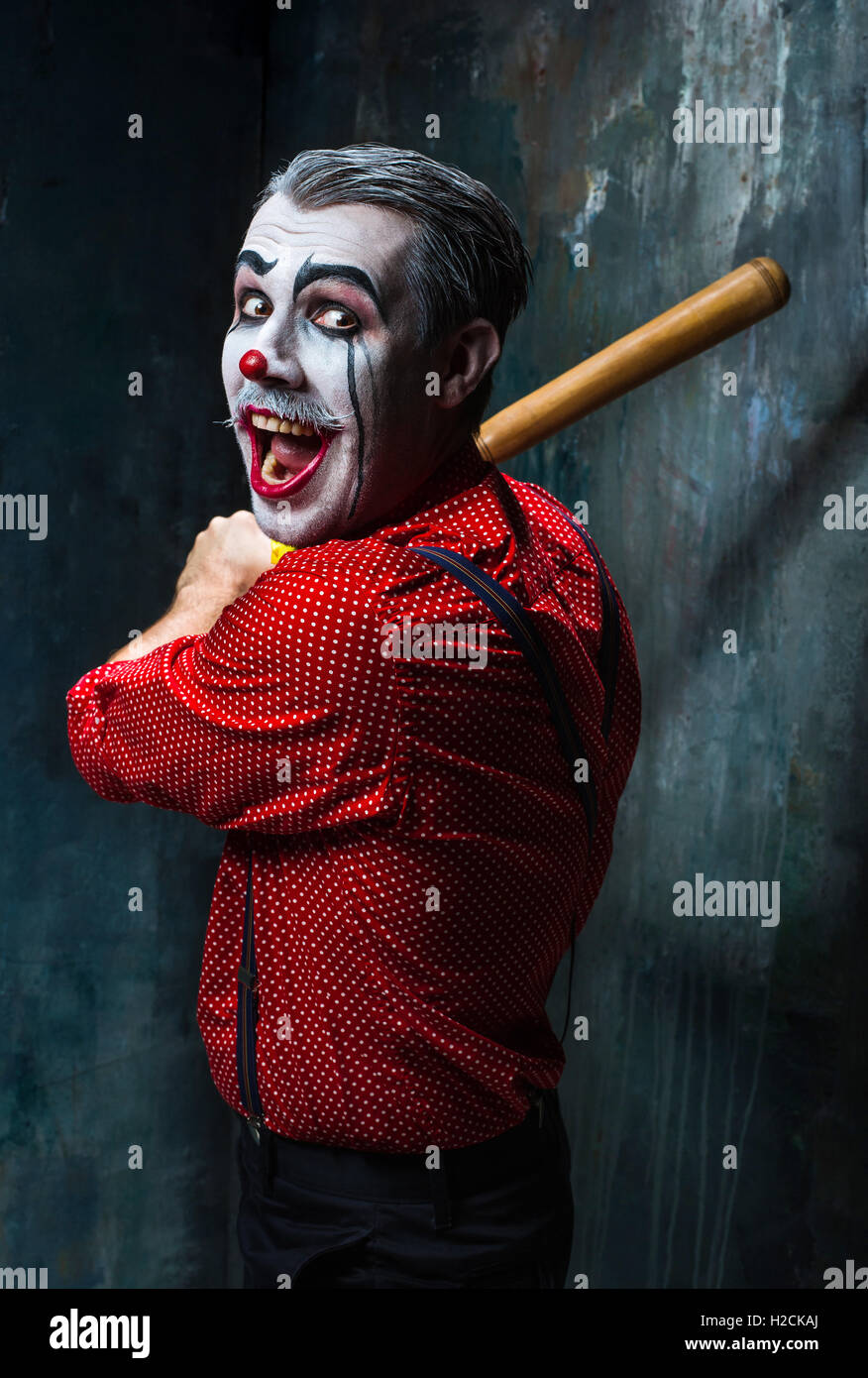 The scary clown and baseball-bat on dack background. Halloween concept ...