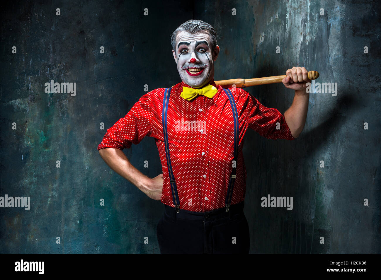 The scary clown and baseball-bat on dack background. Halloween concept ...