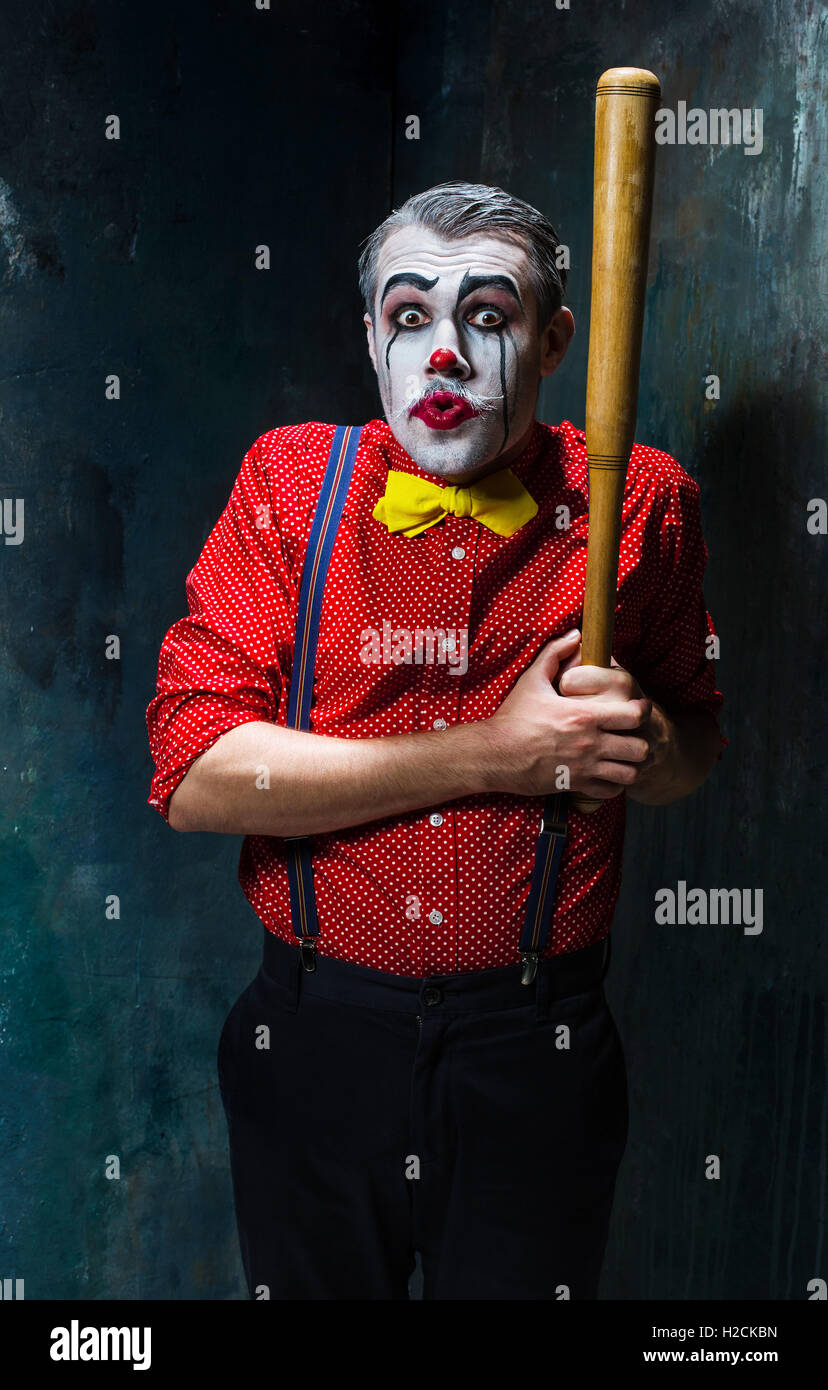 The scary clown and baseball-bat on dack background. Halloween concept ...